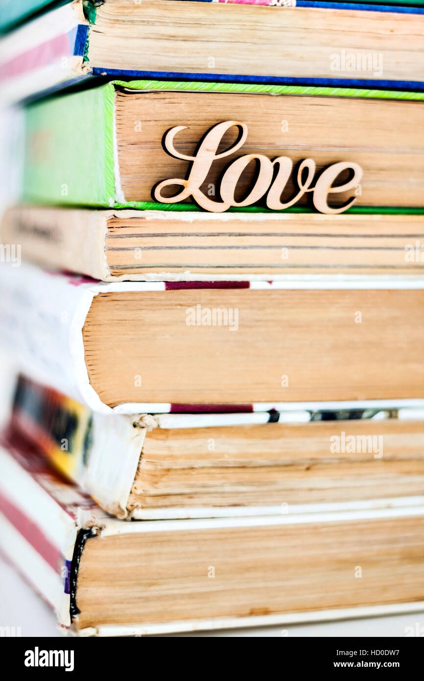 on a stack of old books wooden word love Stock Photo - Alamy