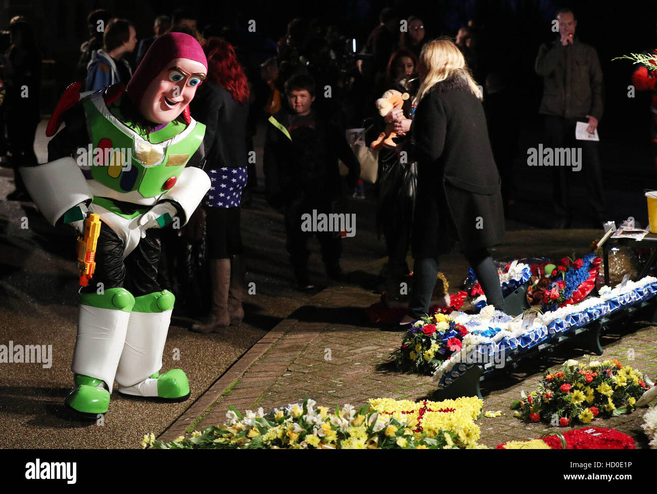 A mourner dressed as Buzz Lightyear looks at floral tributes during the ...