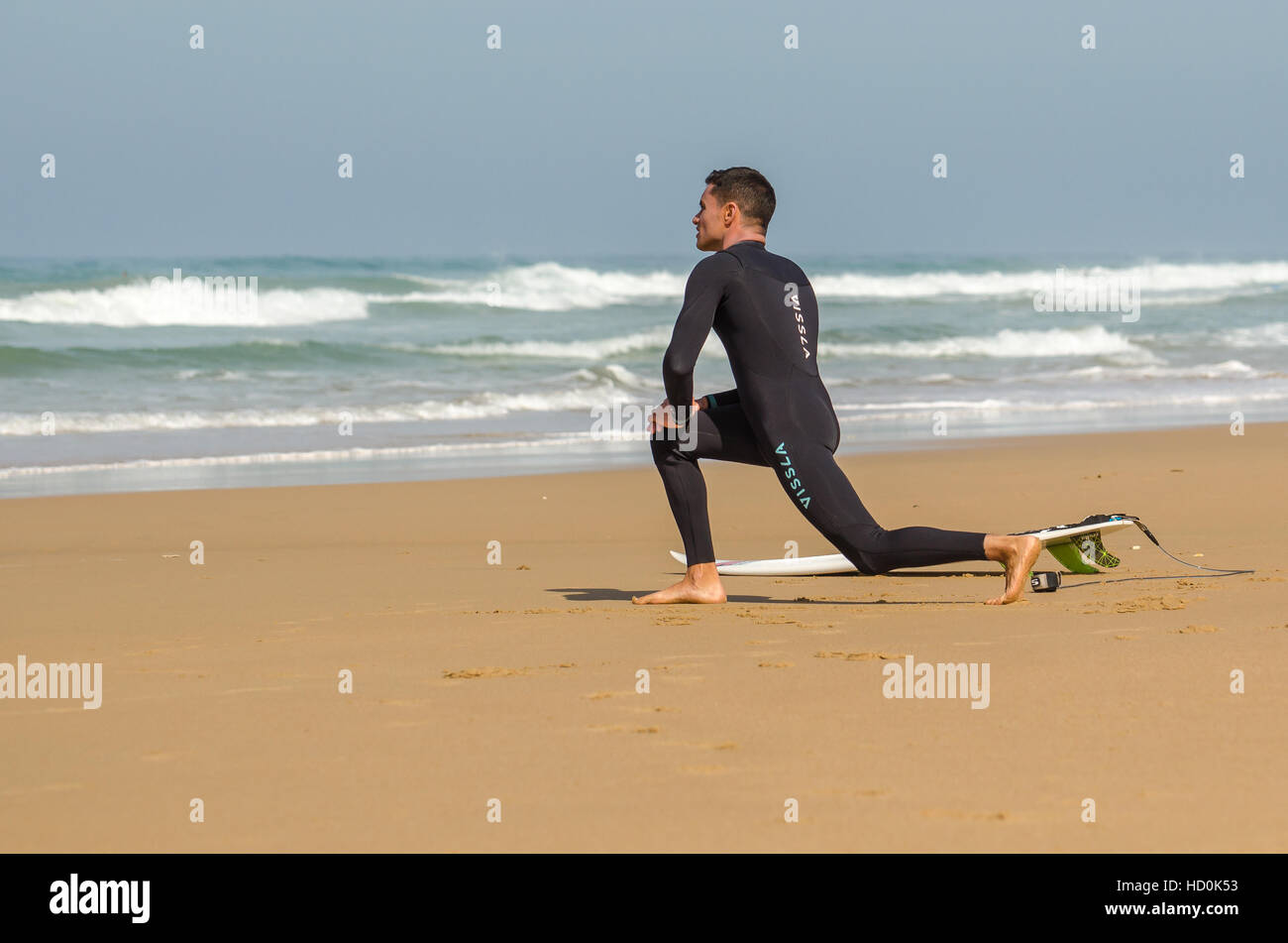 A surfer stretches out on the beach before a morning surf Stock Photo ...