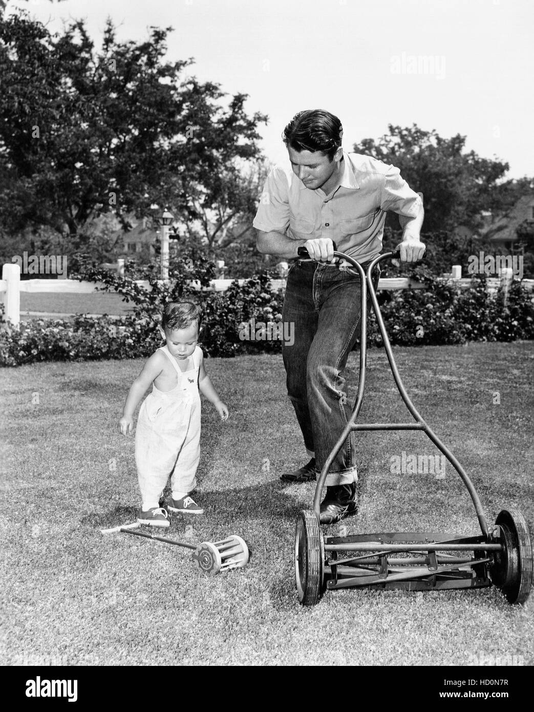Terry Murphy, helping his father, Audie Murphy, mow the lawn at their ...