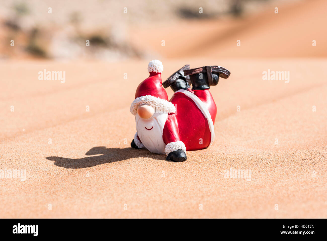Funny Santa Claus figurine appearing to slide on the sand, in the ...