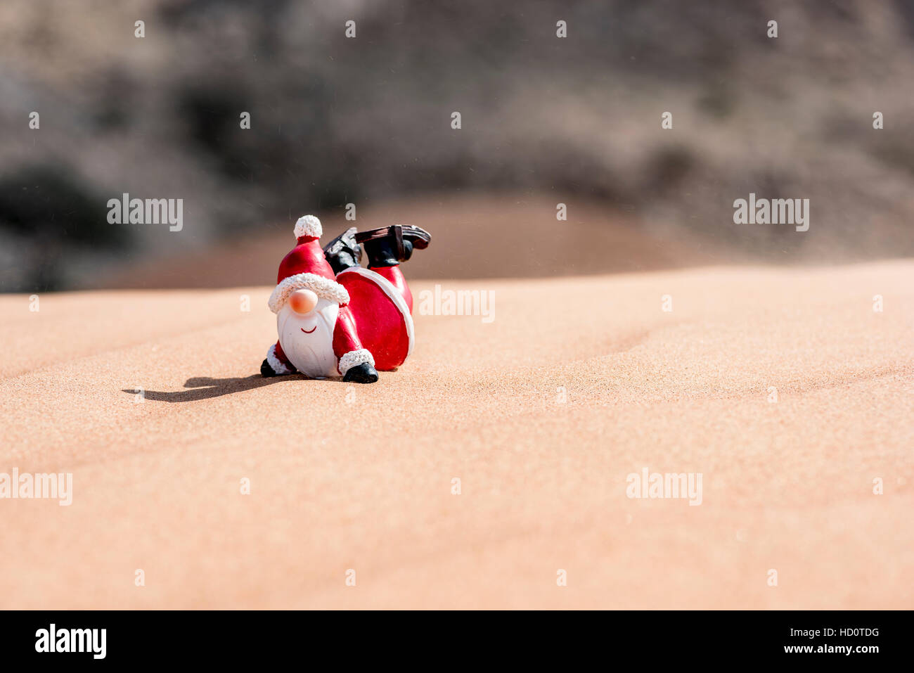Santa Claus figurine comically sliding on desert sand, blending festive ...