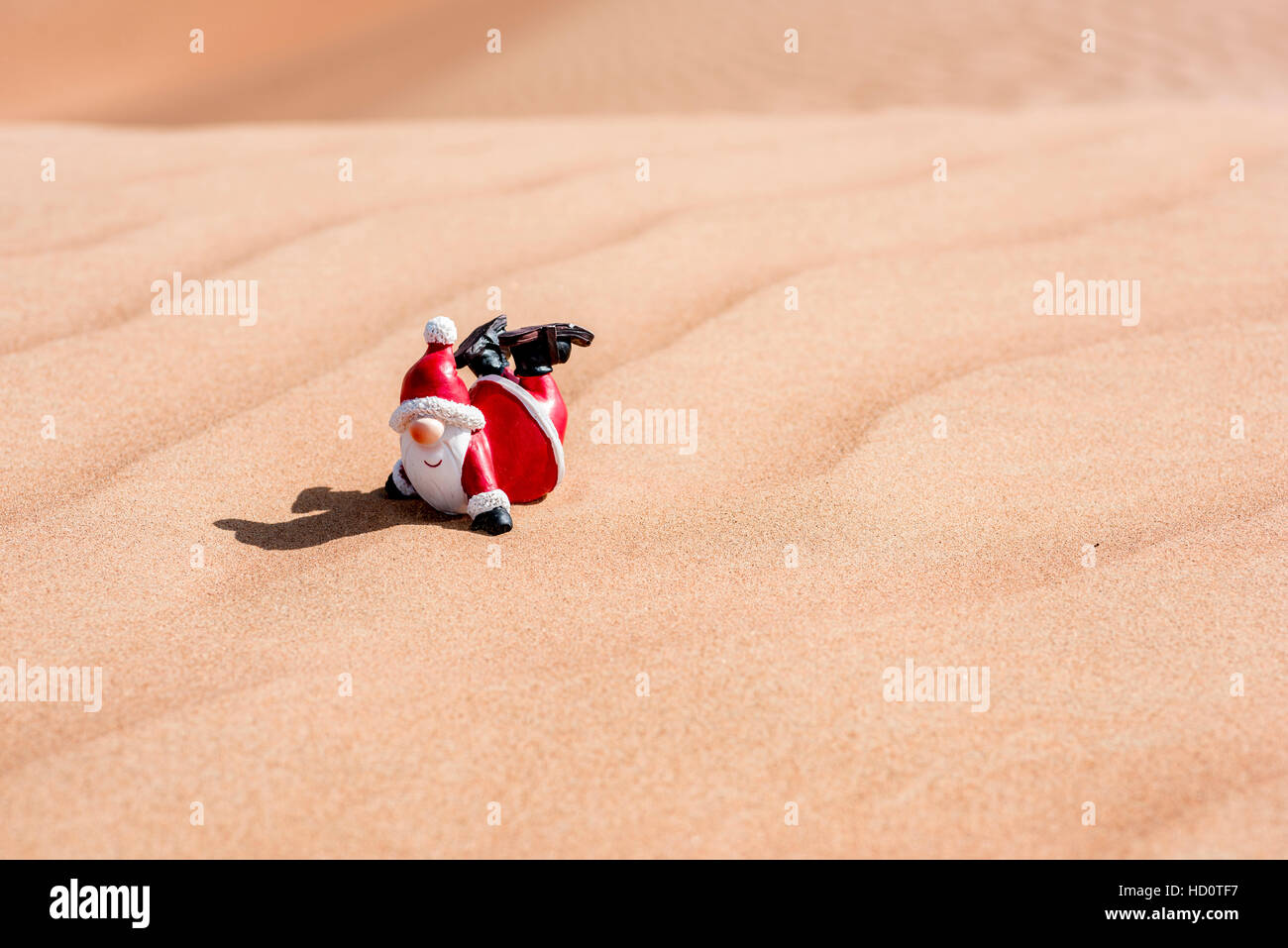 Santa Claus figurine comically sliding on desert sand, blending festive ...
