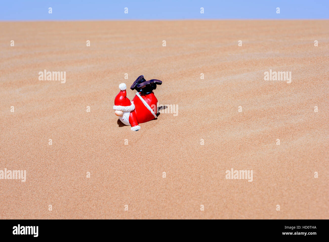 Santa Claus figurine comically sliding on desert sand, blending festive ...
