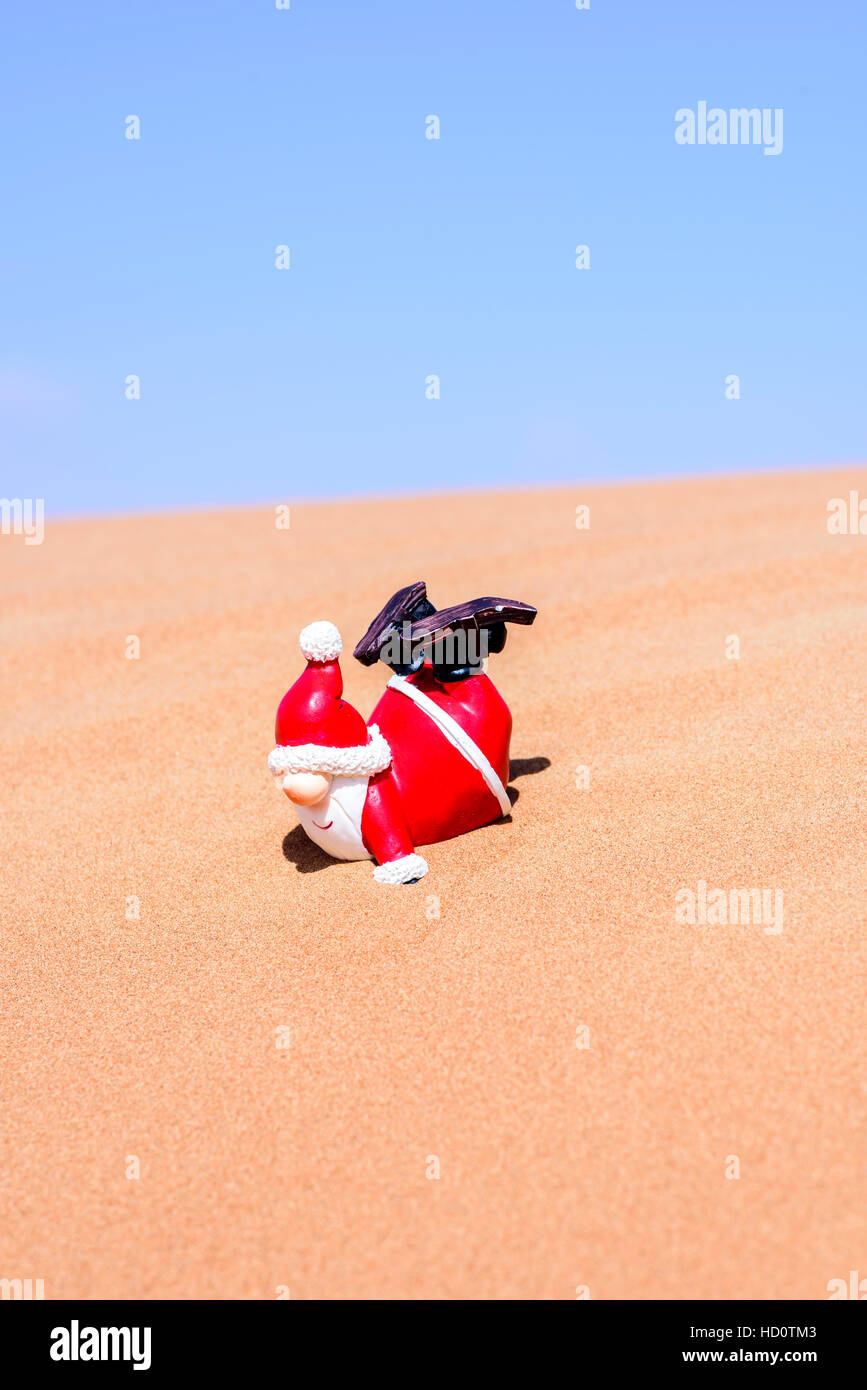 Santa Claus figurine comically sliding on desert sand, blending festive ...