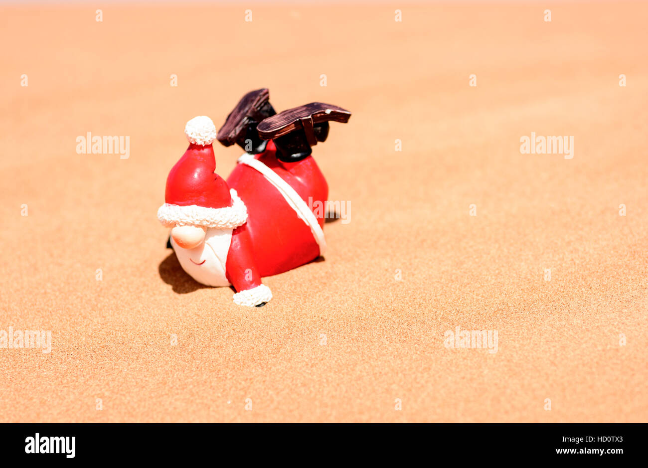 Santa Claus figurine comically sliding on desert sand, blending festive ...