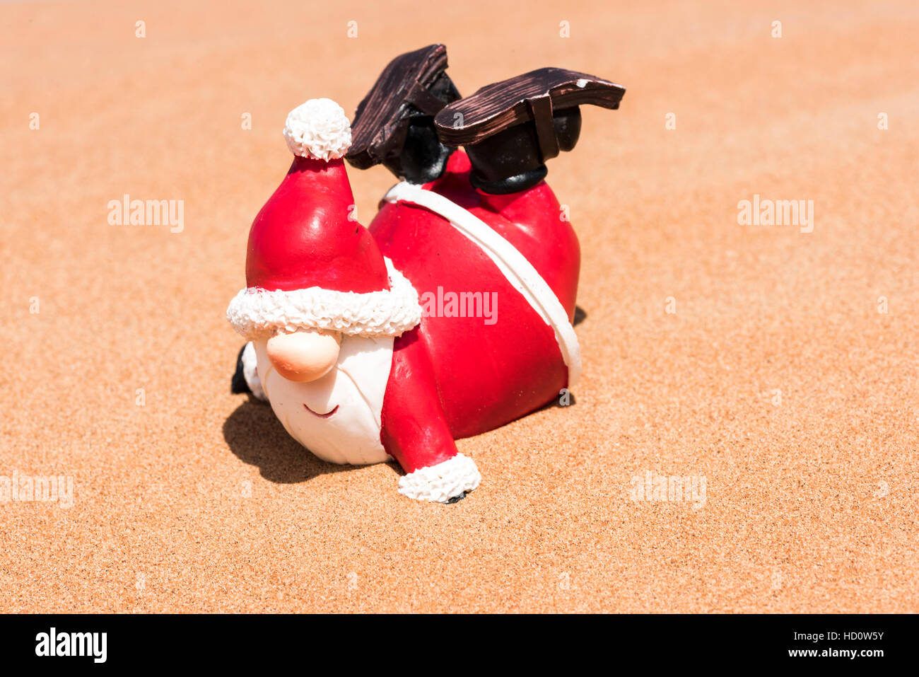 Santa Claus figurine comically sliding on desert sand, blending festive ...