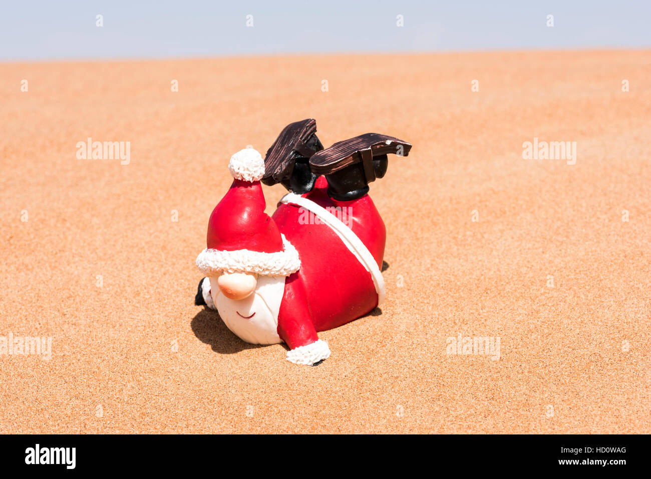 Santa Claus figurine comically sliding on desert sand, blending festive ...