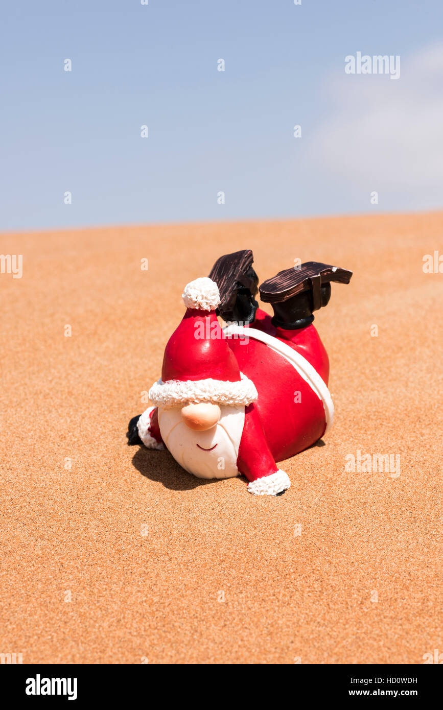 Santa Claus figurine comically sliding on desert sand, blending festive ...