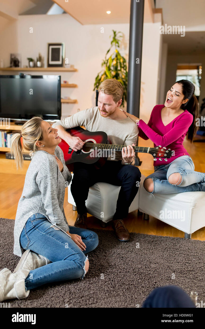 Happy friends playing guitar and listening to music at home Stock Photo ...