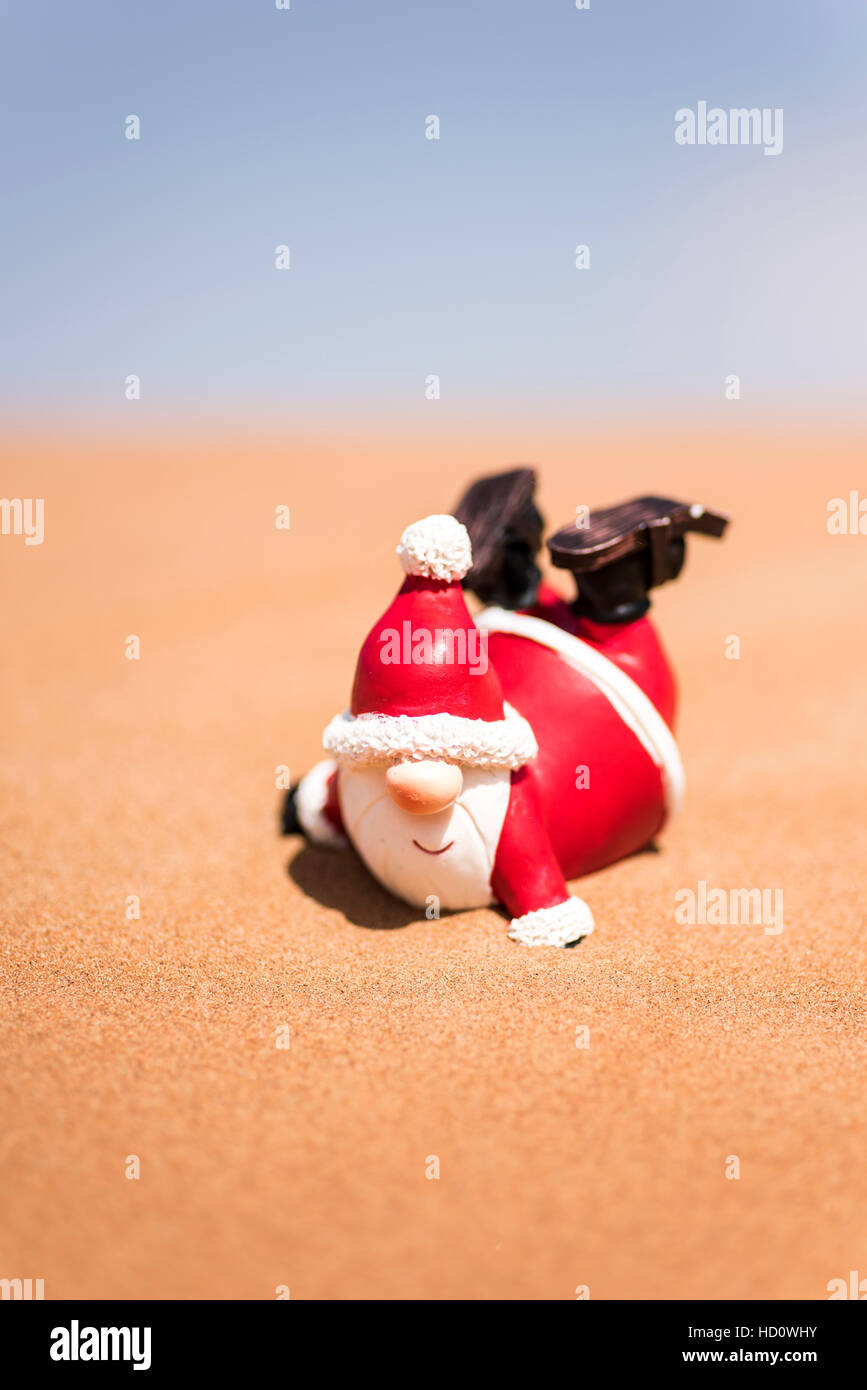 Santa Claus figurine comically sliding on desert sand, blending festive ...