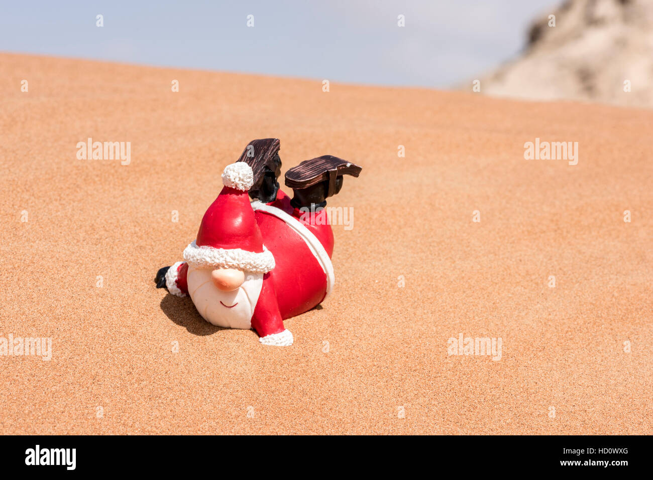 Santa Claus figurine comically sliding on desert sand, blending festive ...