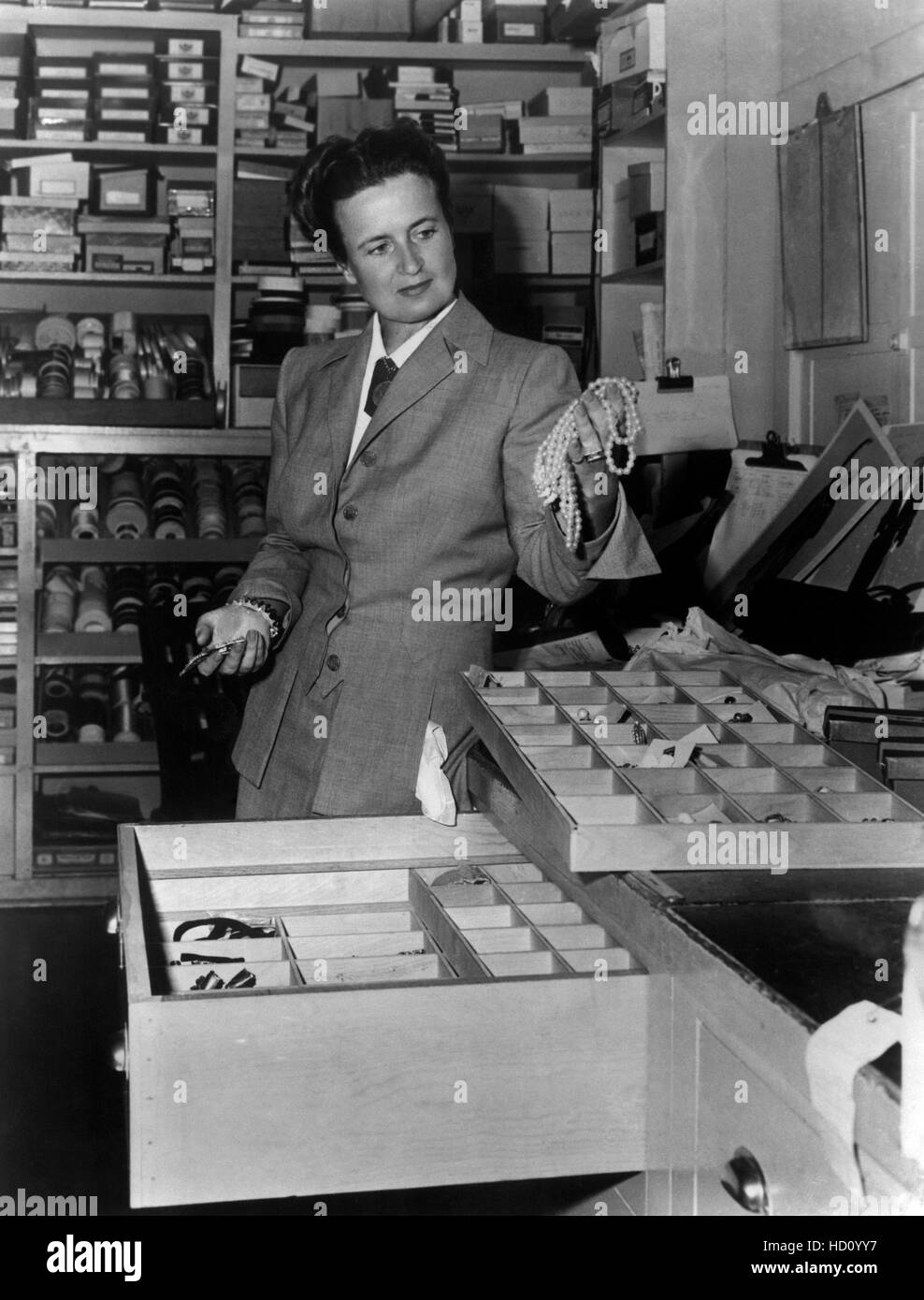 Irene Lentz examining a pearl necklace in the wardrobe department at ...