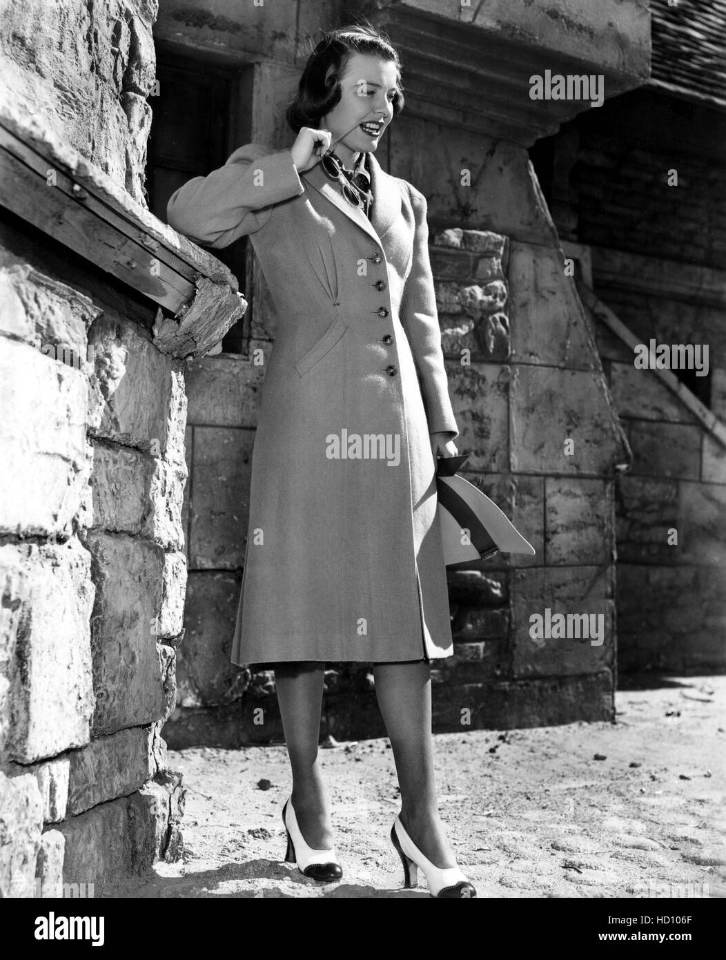 Jane Bryan, wearing a lightweight coat of beige wool, fitted with darts ...