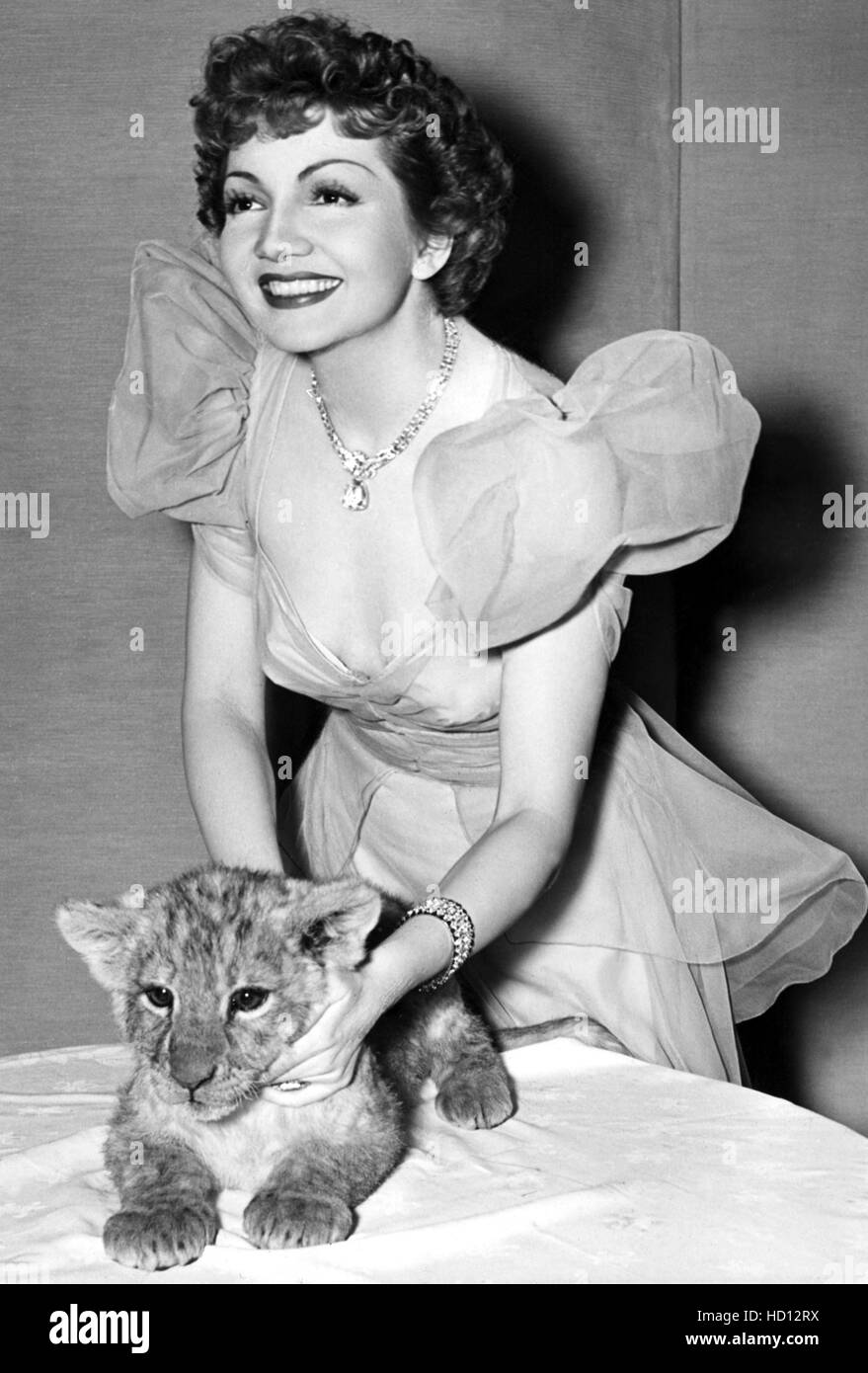 CLAUDETTE COLBERT poses with lion cub - a direct descendant of MGM's ...