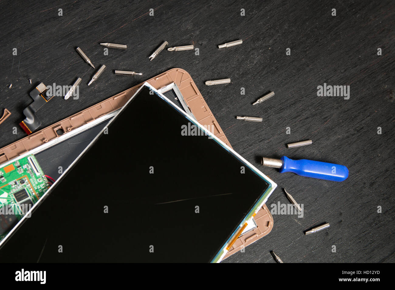 Process of PC Tablet device repair near screwdriver and bit on black ...