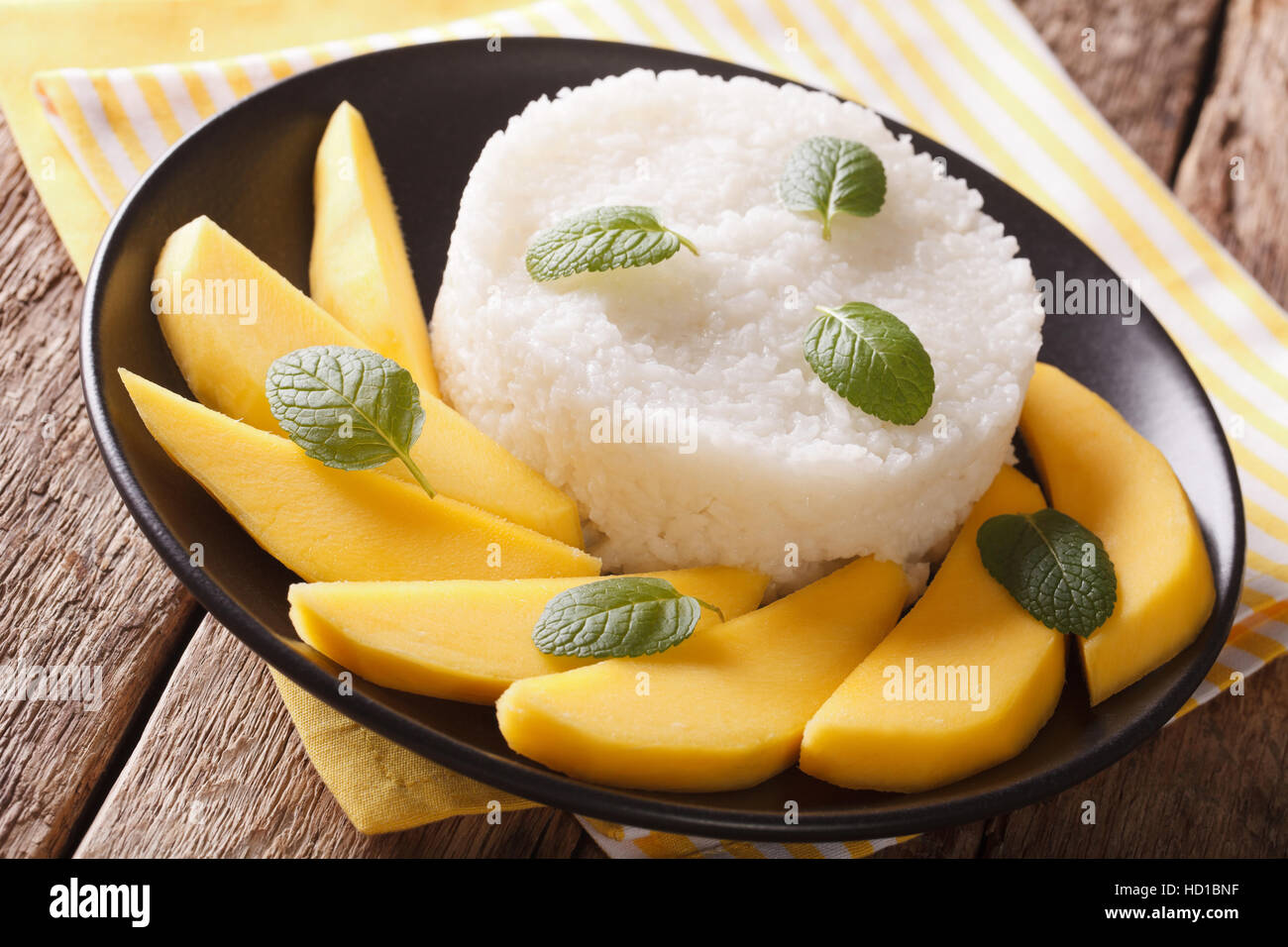 Glutinous rice with ripe mango close-up on a plate on the table ...