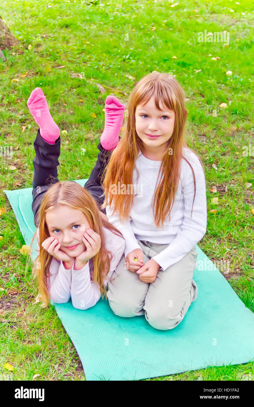 Photo of two girls sitting on grass in summer Stock Photo - Alamy