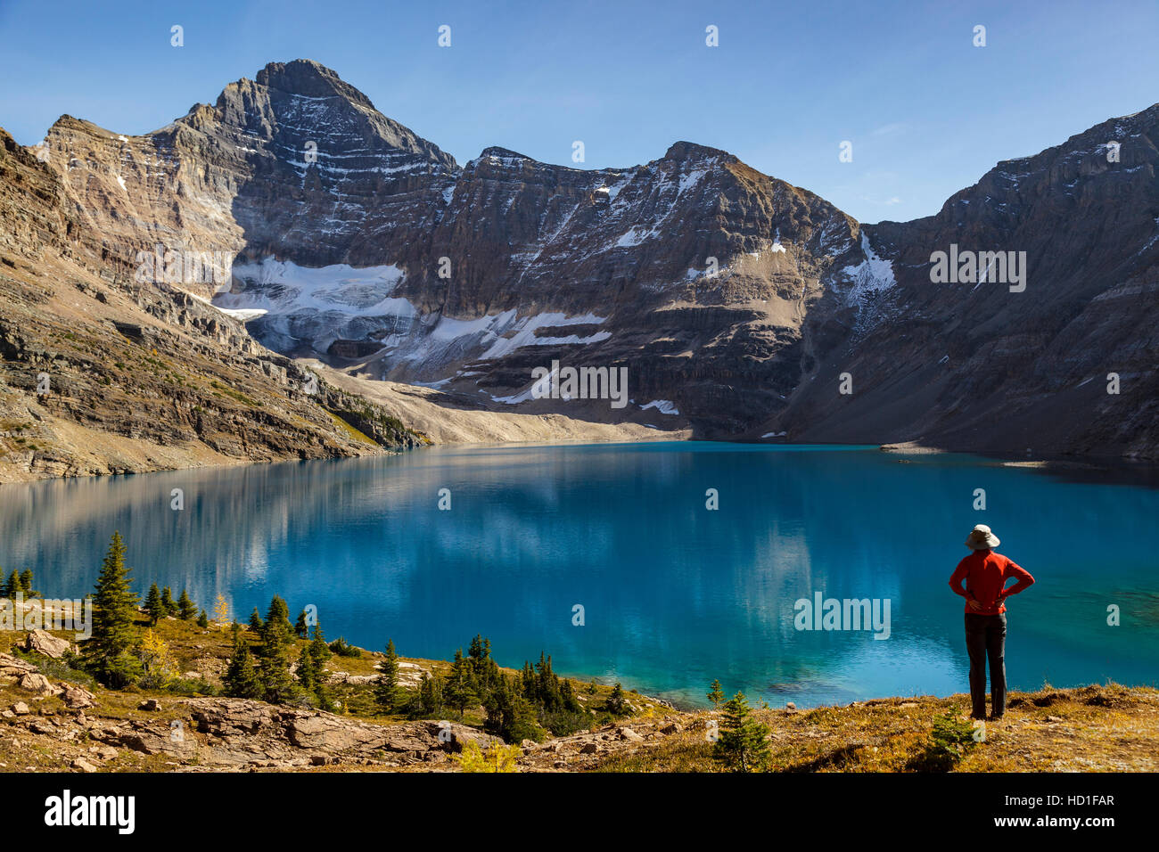 A solitary hiker stands on the shore of lake McArthur in Yoho National ...