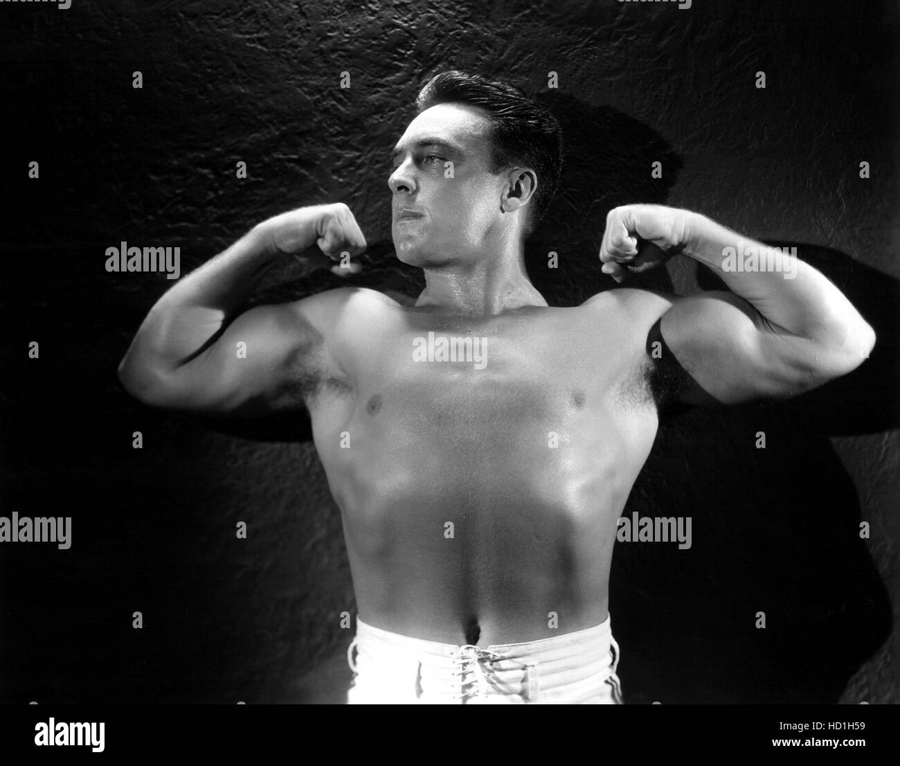 GEORGE O'BRIEN flexes his muscles for a Fox publicity shot, mid 1920s, TM and Copyright (c) 20th ...