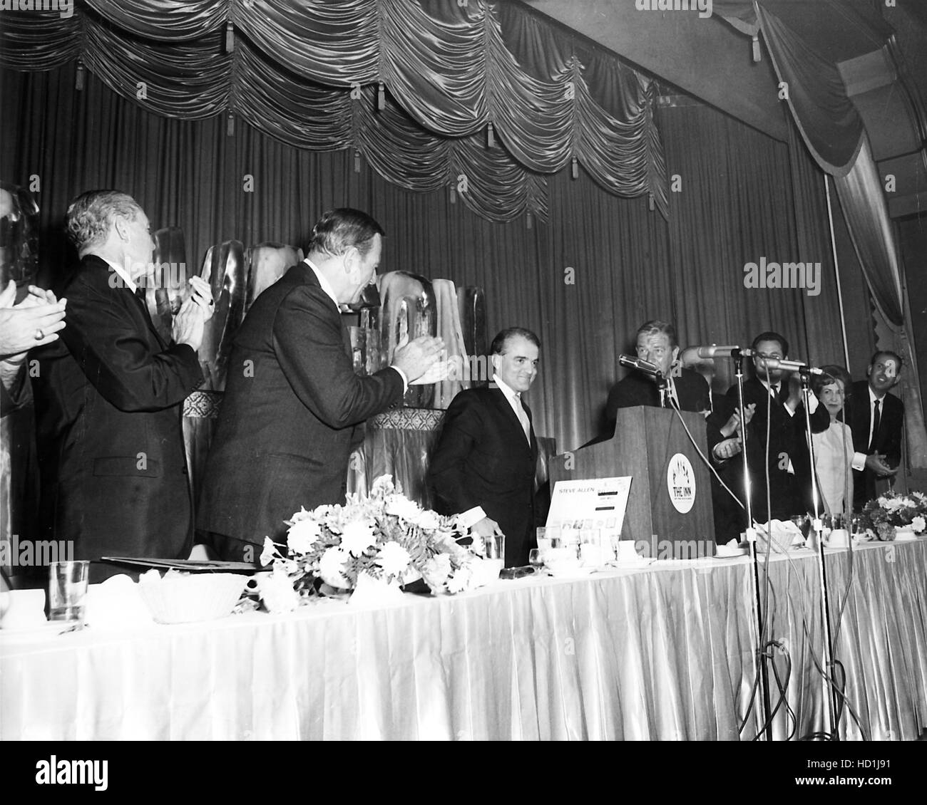 Jack Valenti, (C), is congratulated by John Wayne, (L), and others at ...