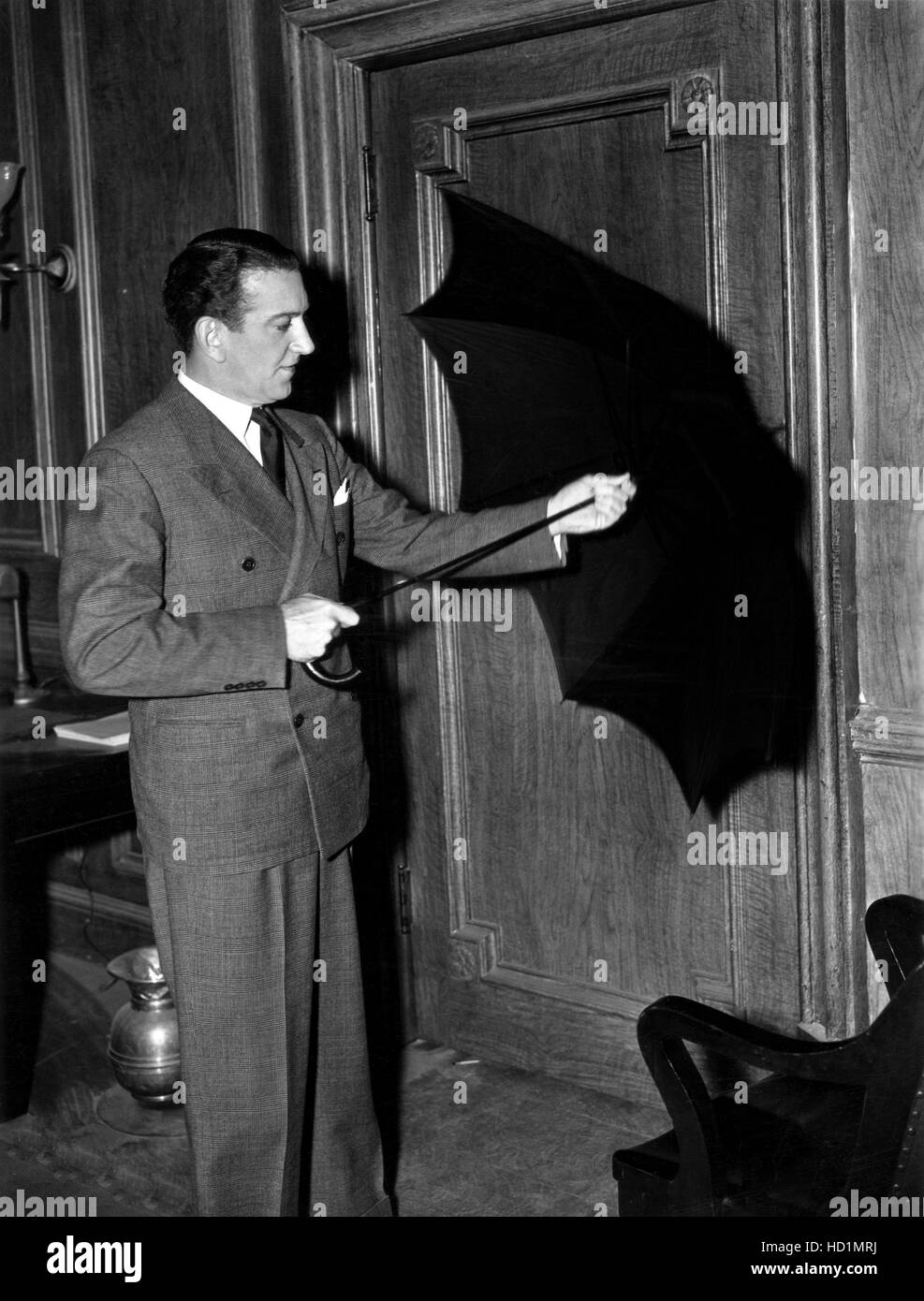 John Litel opens an umbrella indoors, circa 1950s Stock Photo - Alamy