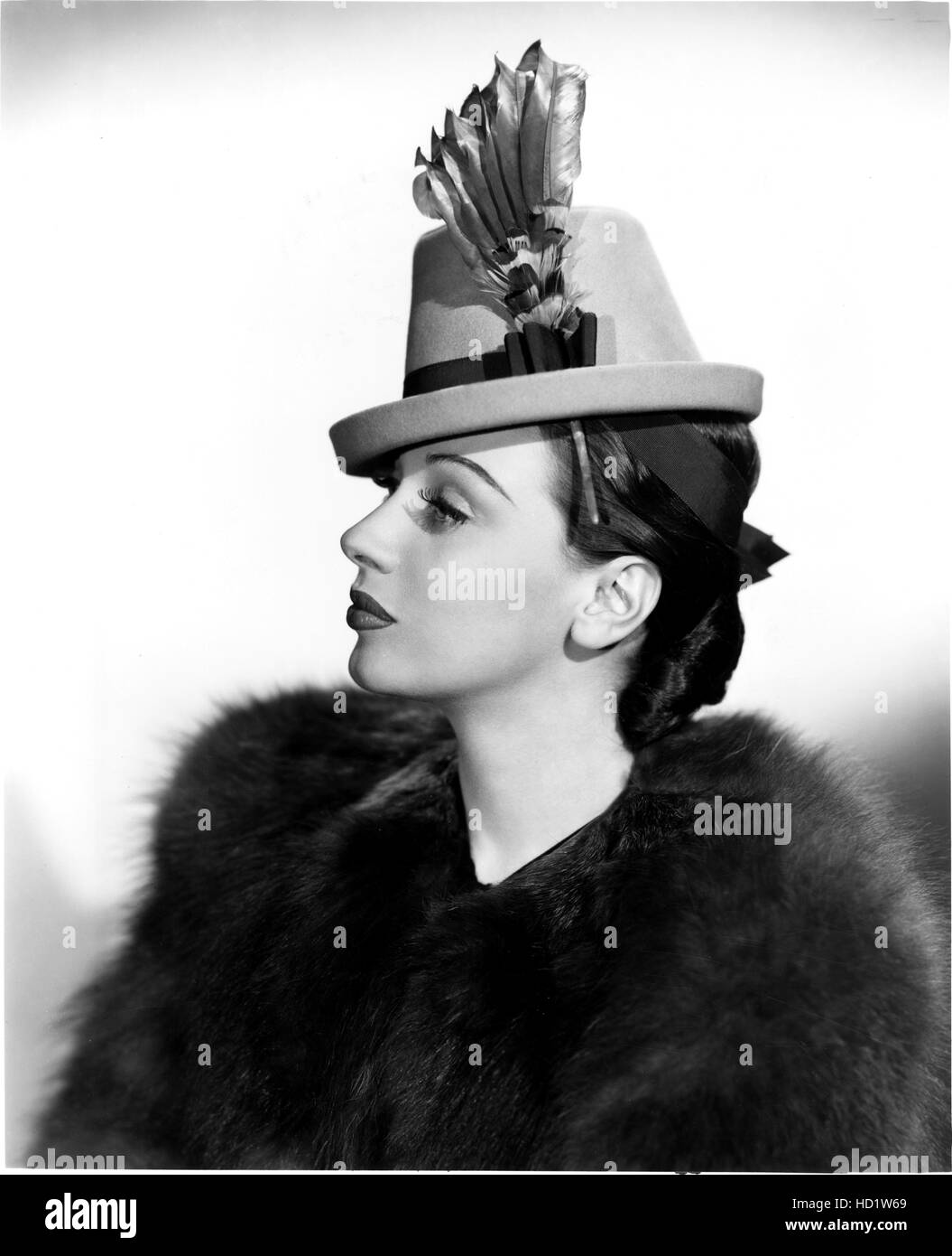 Patricia Morison, modeling a beige 'custard cup' hat trimmed with red ...