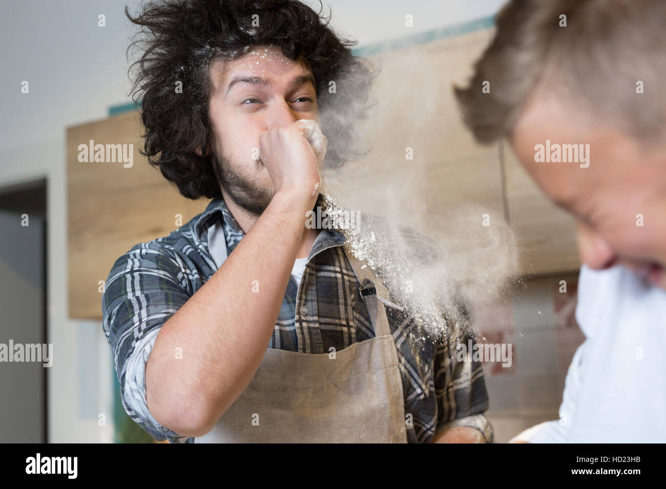 a father and his son preparing a cake in the kitchen. Father and son ...