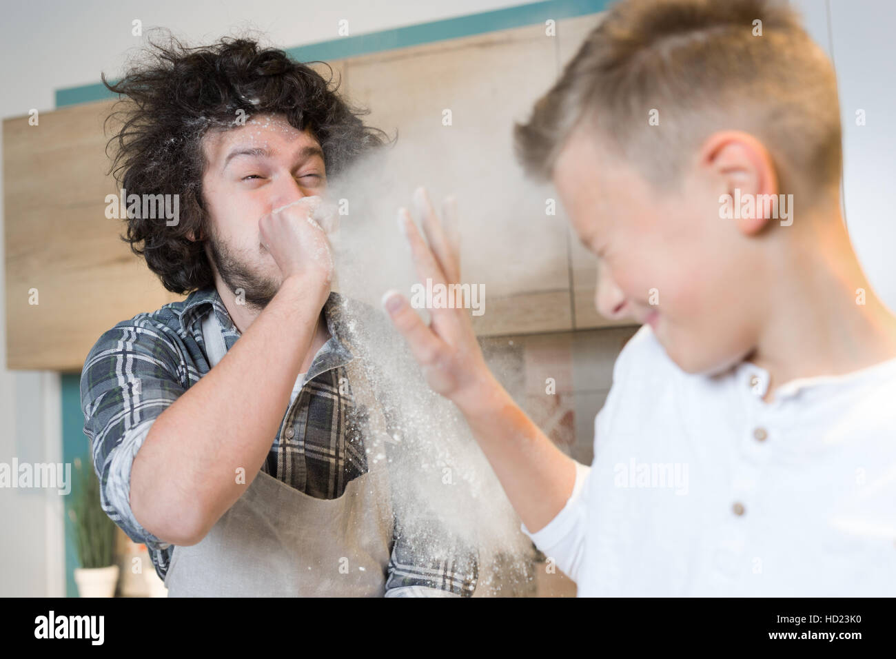 Flour fight in kitchen. Father and his son preparing a cake in the ...