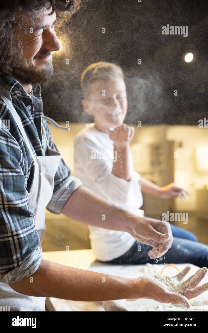 Flour fight in kitchen. Father and his son preparing a cake in the ...