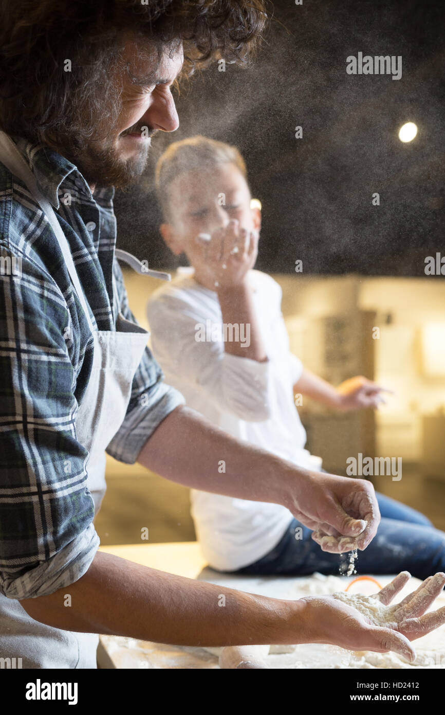 Flour fight in kitchen. Father and his son preparing a cake in the ...