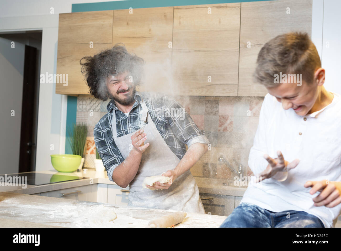 Flour fight in kitchen. Father and his son preparing a cake in the ...