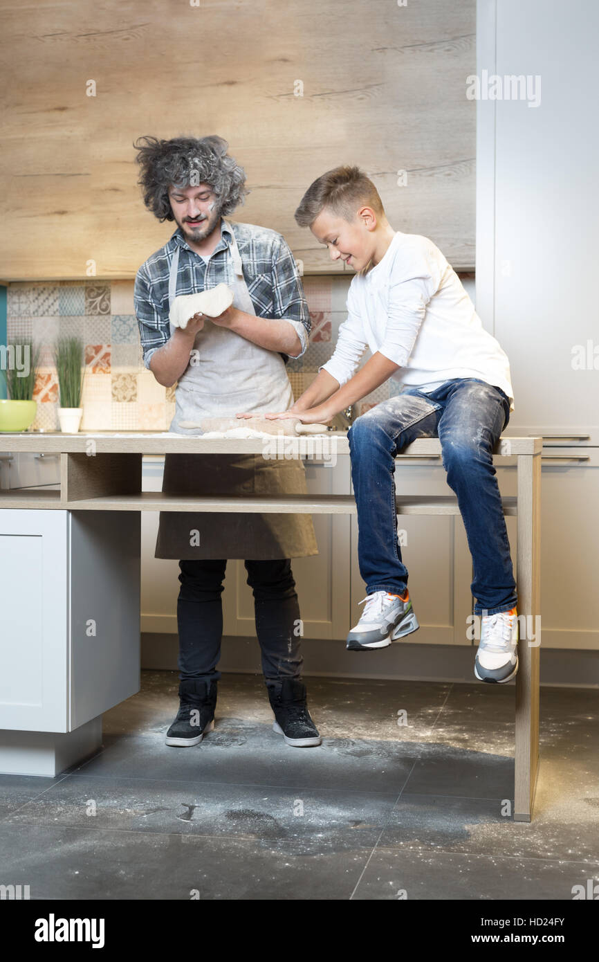 a father and his son preparing a cake in the kitchen, flour fight in ...