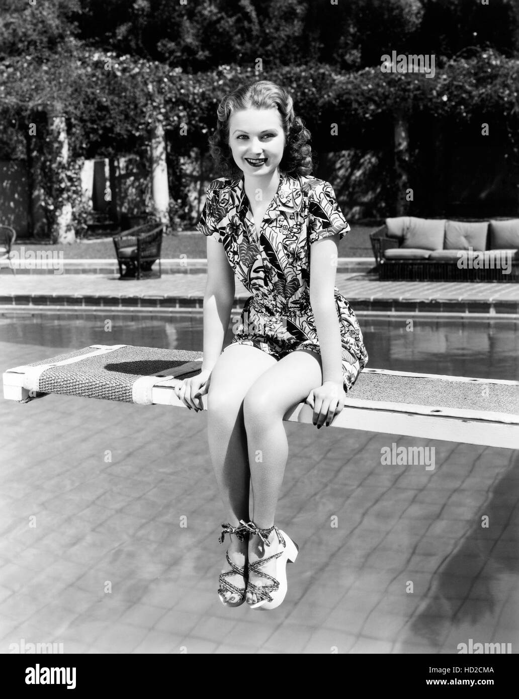 June Lang wears a tropical print playsuit and platform sandals, ca. mid ...
