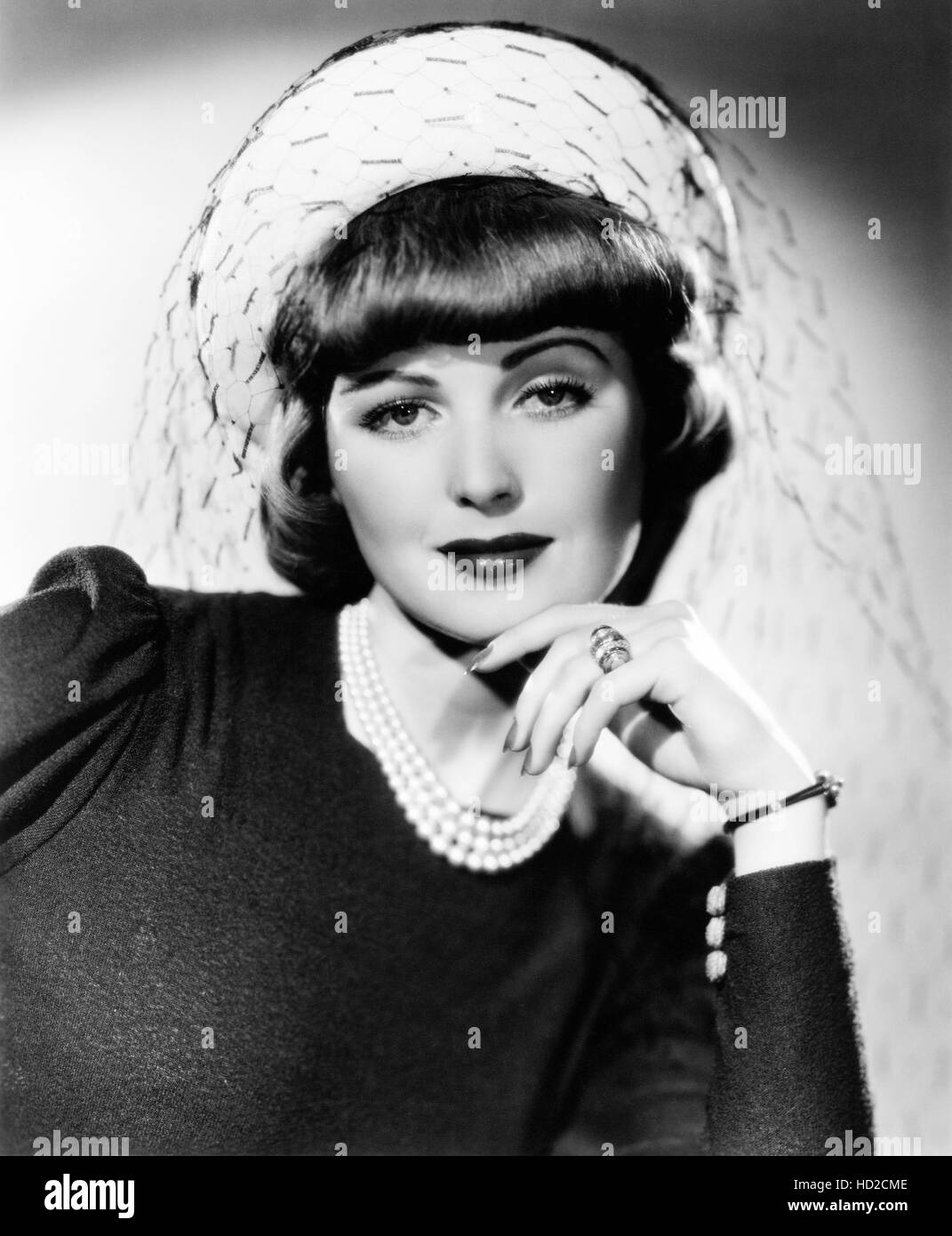 June Lang wears a white baku hat draped with a black veil embroidered ...