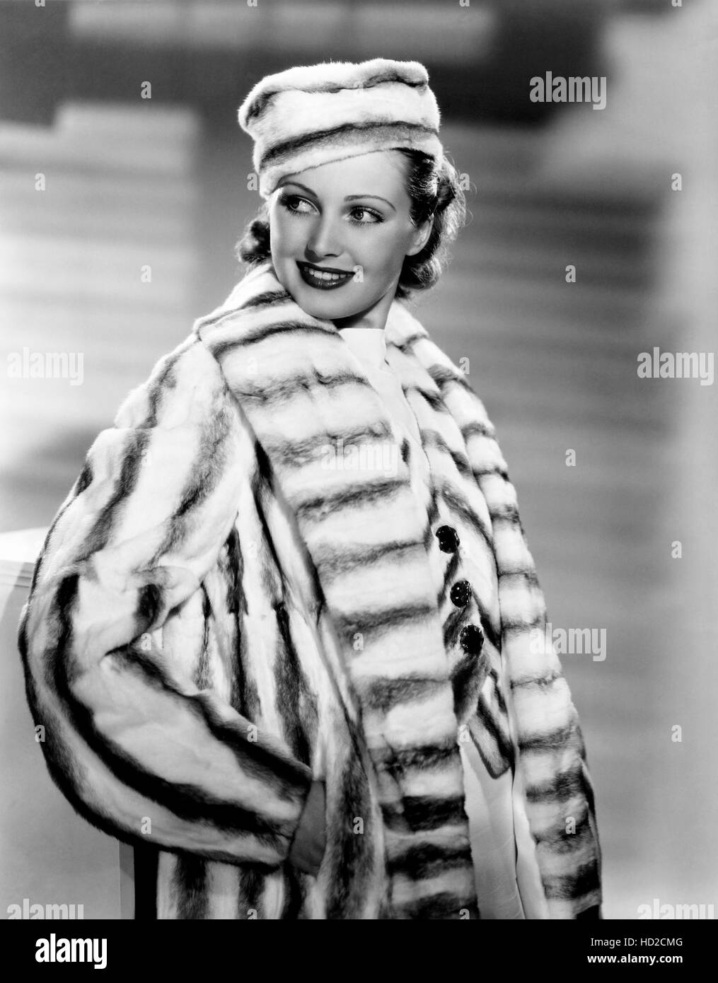 June Lang wears a three-quarter length light brown striped fur coat ...