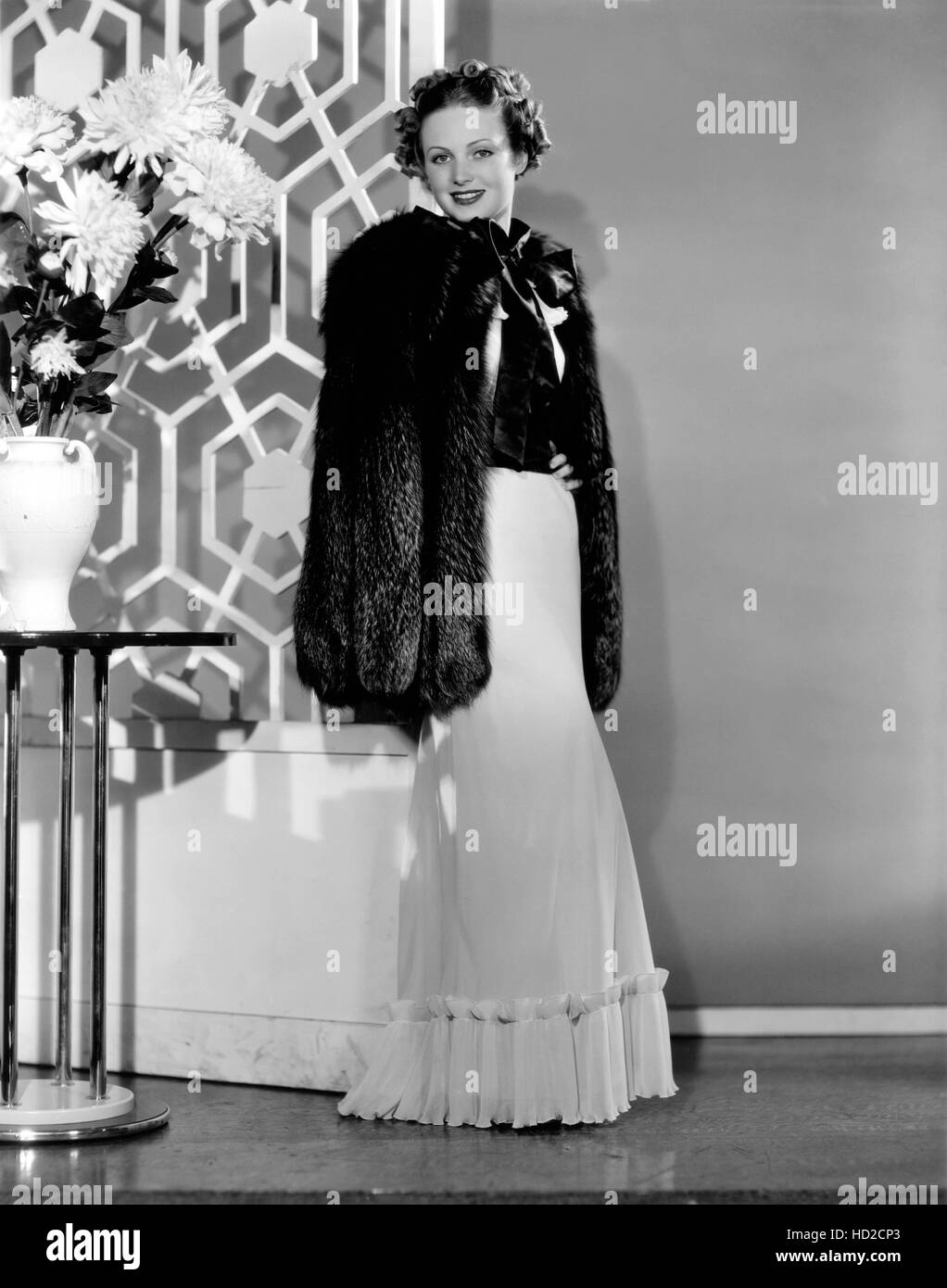 June Lang wears a silver fox cape over an ivory chiffon evening gown ...