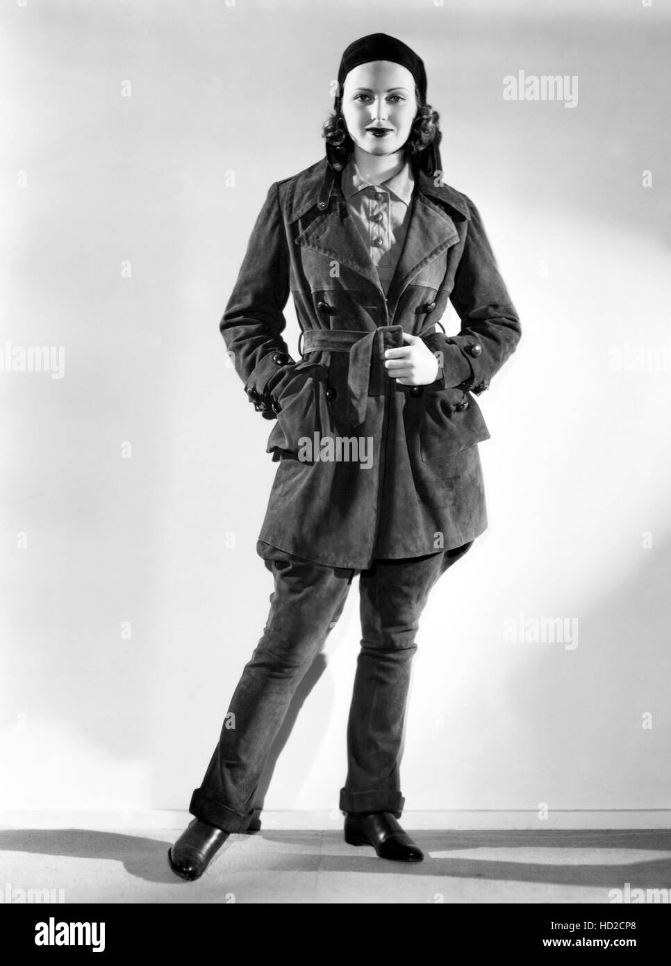 June Lang wears a flying suit of brown suede pants and belted coat ...