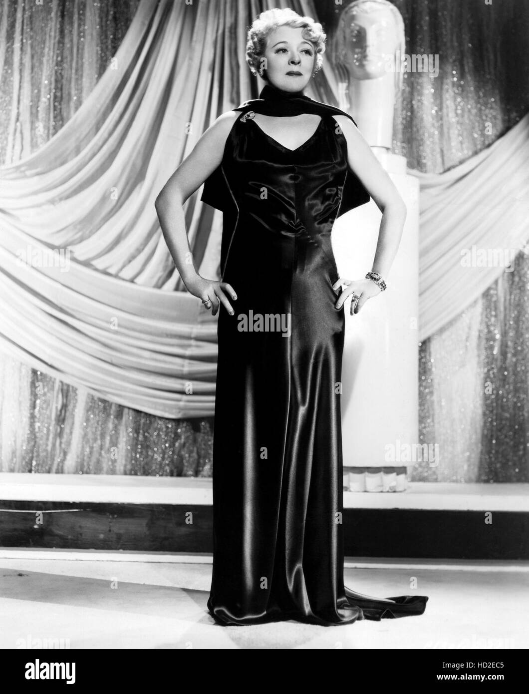 Mary Boland modeling black satin formal with matching capelet, ca. 1936 ...