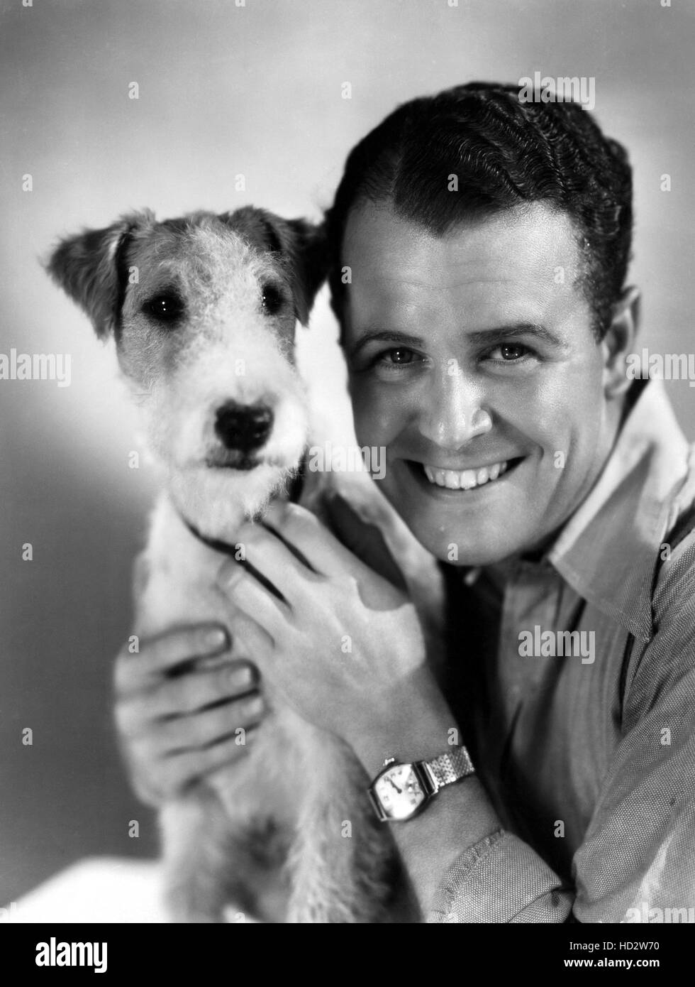 Regis Toomey posing with wire haired terrier, ca. 1930s Stock Photo - Alamy