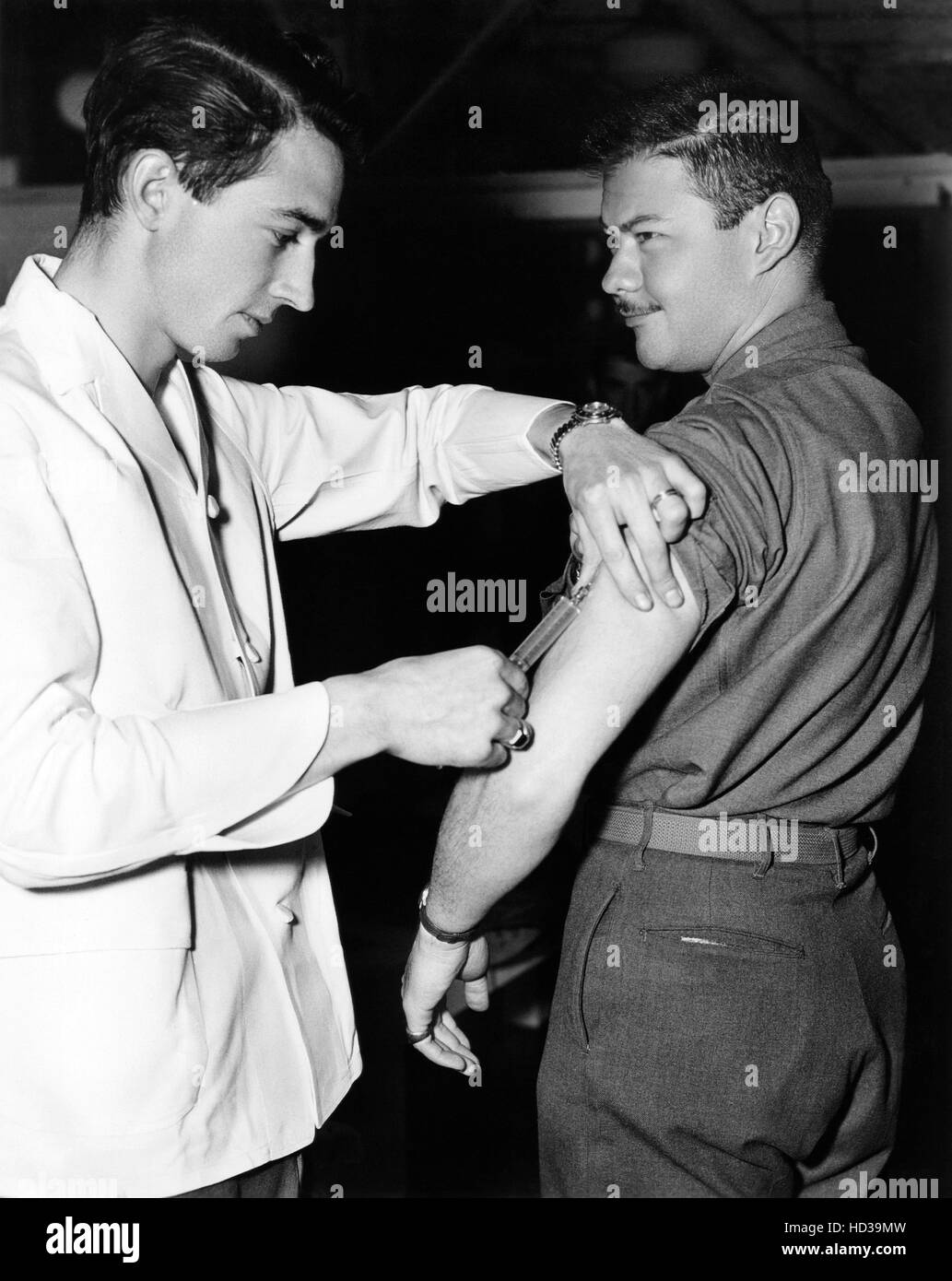 From left: William R. Babbitt giving Turhan Bey a cholera shot before ...