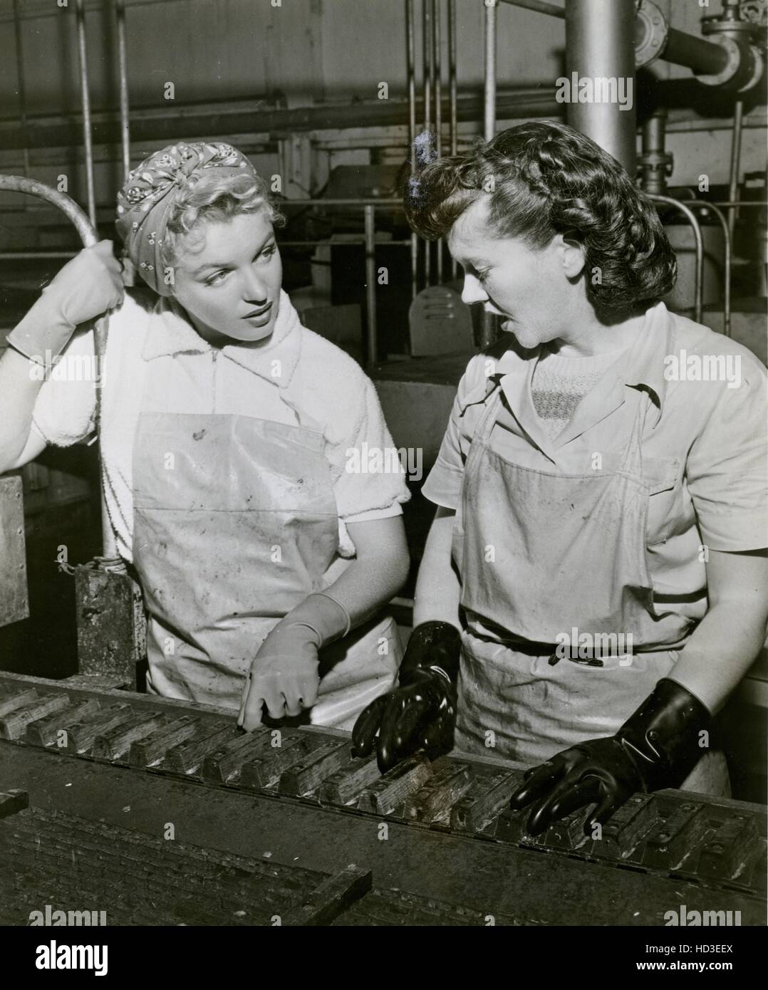 Marilyn Monroe, left, being shown how to work the assembly line while ...