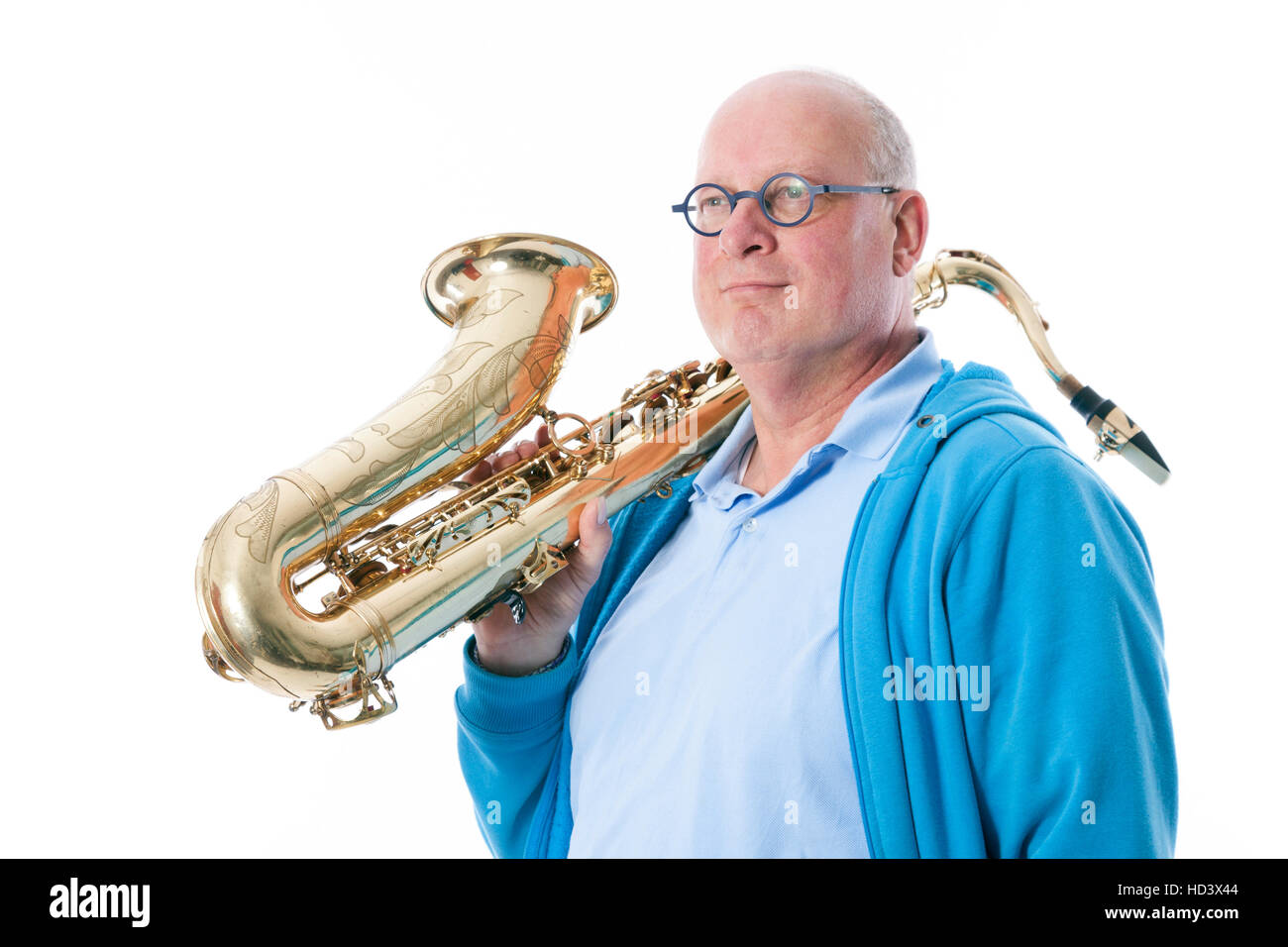 middle aged man in blue plays the tenor saxophone against white studio ...