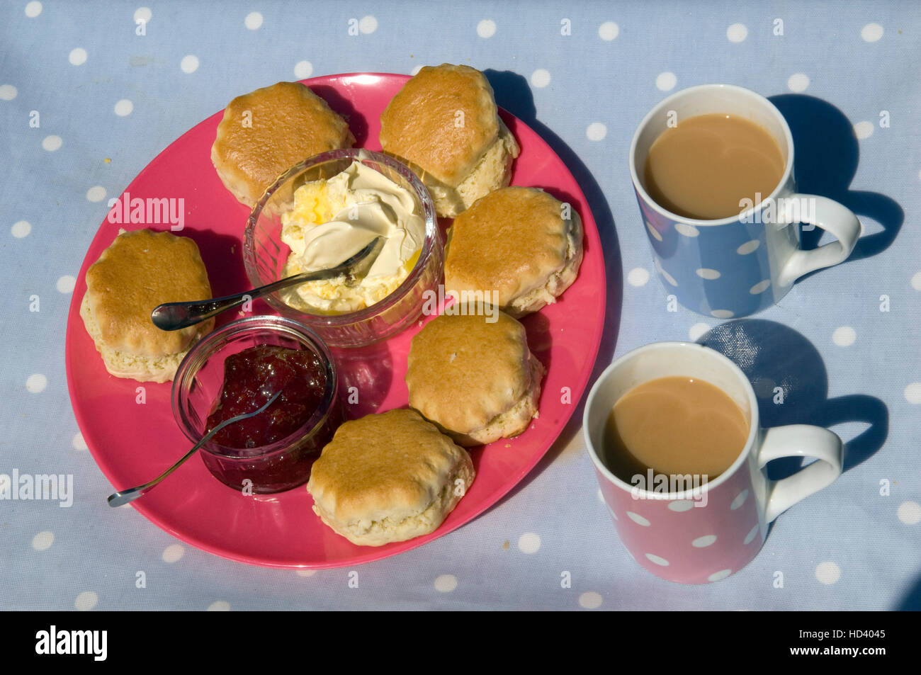 An informal cream tea with scones, cream, jam and 2 mugs of tea on a ...
