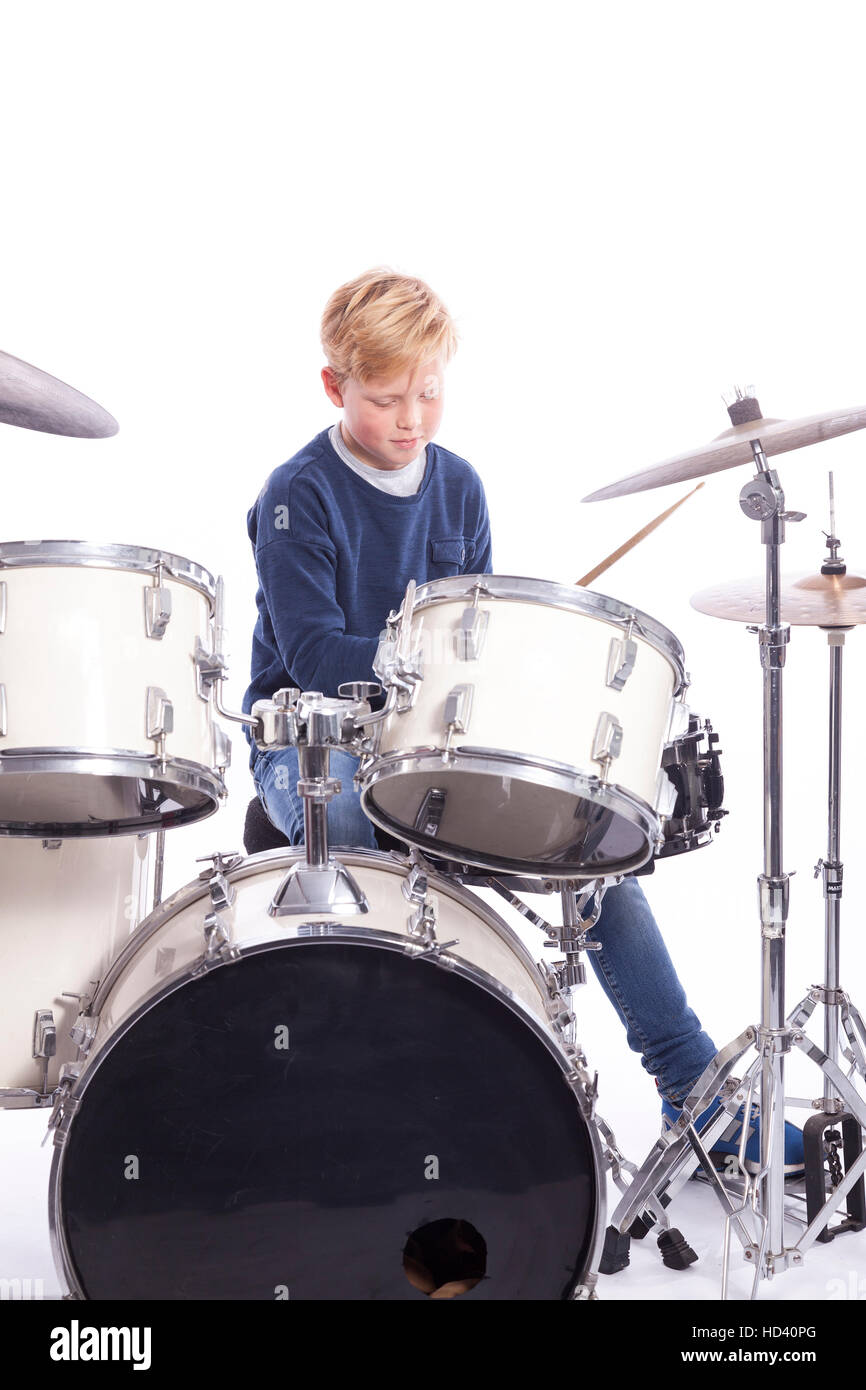 young blond boy drums behind drum kit against white background in ...