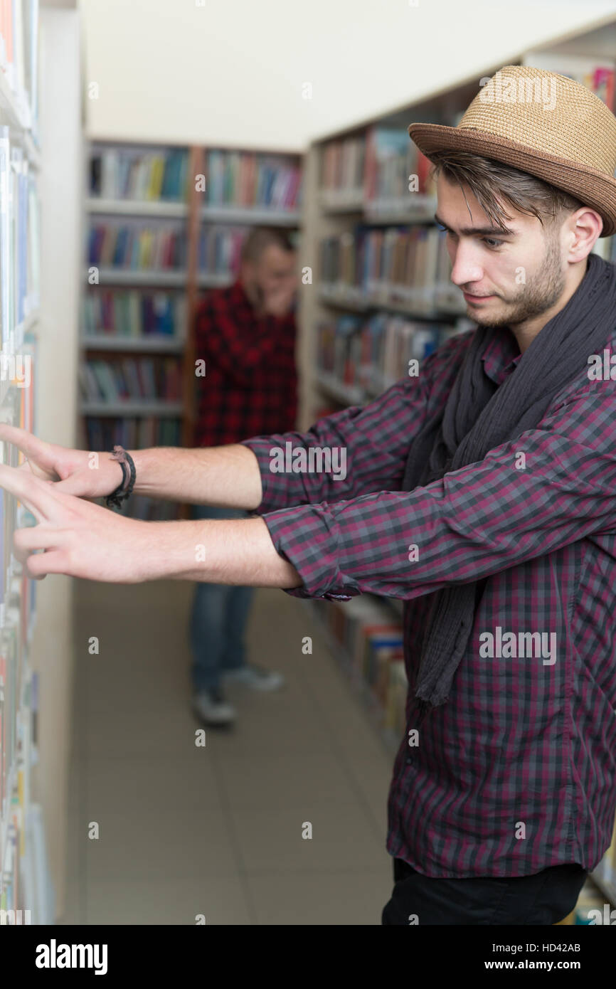 male college student taking book from shelf in library Stock Photo - Alamy