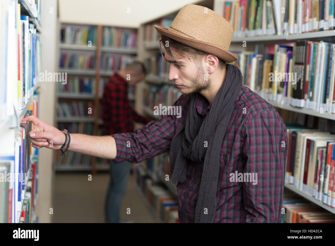 male college student taking book from shelf in library Stock Photo - Alamy