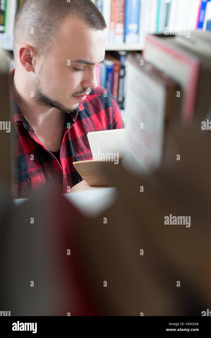 male college student taking book from shelf in library Stock Photo - Alamy