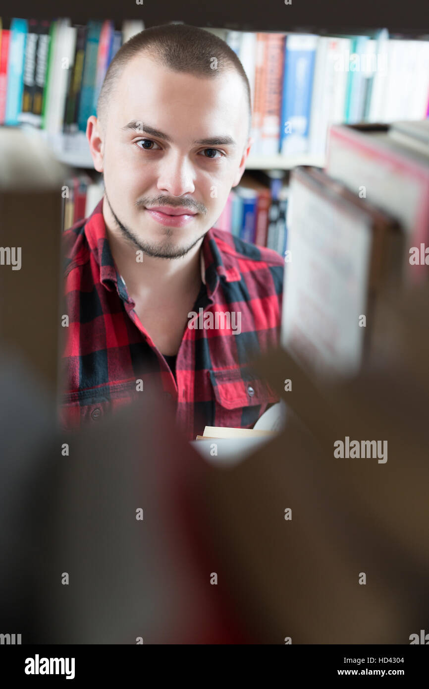 male college student taking book from shelf in library Stock Photo - Alamy