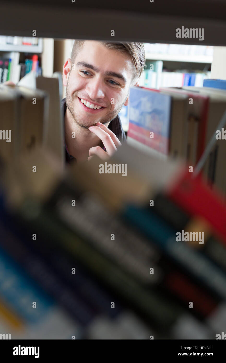 male college student taking book from shelf in library Stock Photo - Alamy